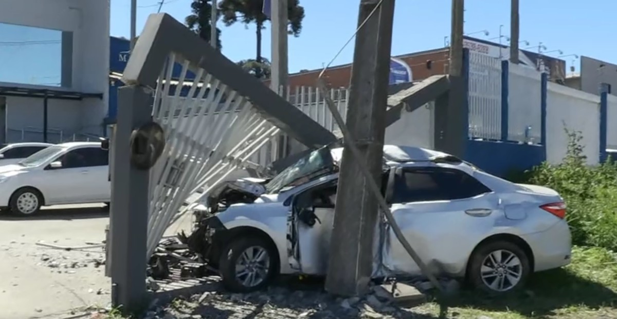 Motorista fica preso nas ferragens após carro bater em poste e portão de empresa, em Curitiba ...